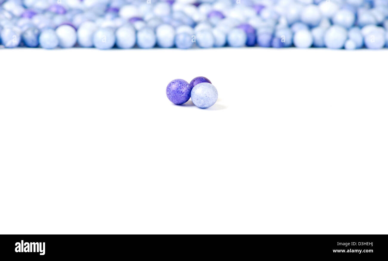 One blue and two violet little pearls isolated on background of other ...
