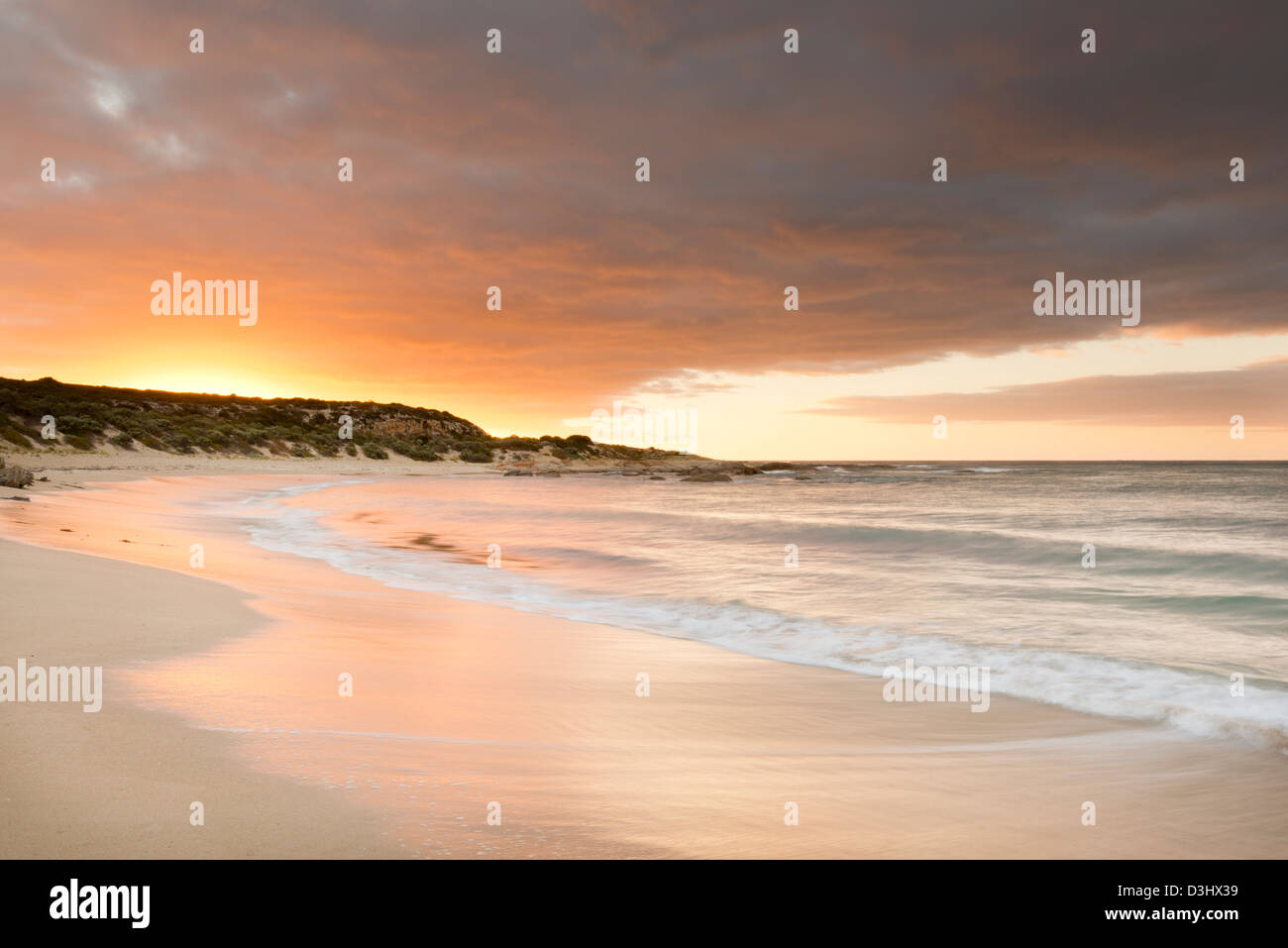 Spectacular sunset over a beach with smooth time-lapse water and sand ...