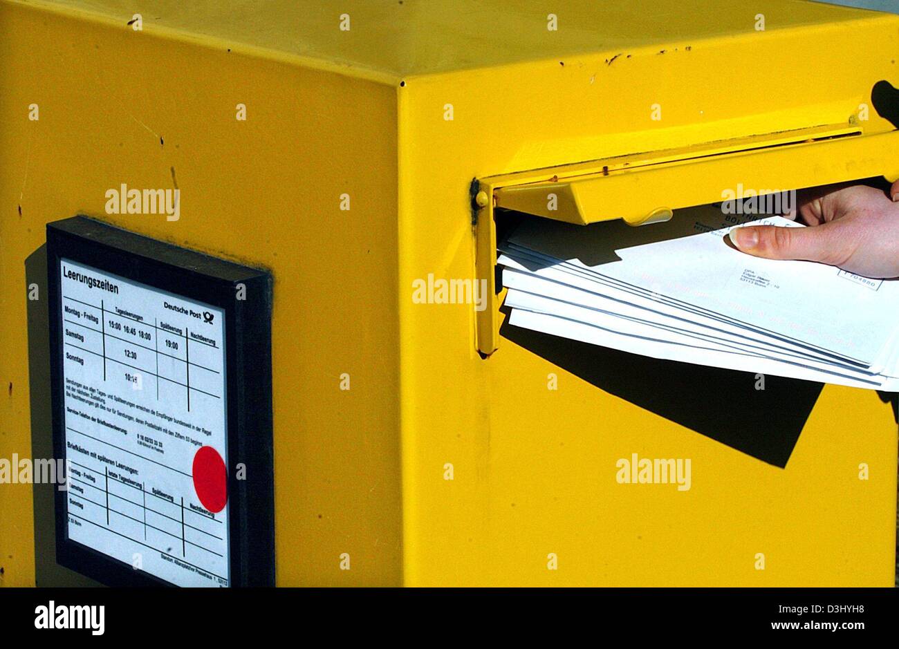 (dpa) - A woman posts letters in a letterbox of the Deutsche Post in ...