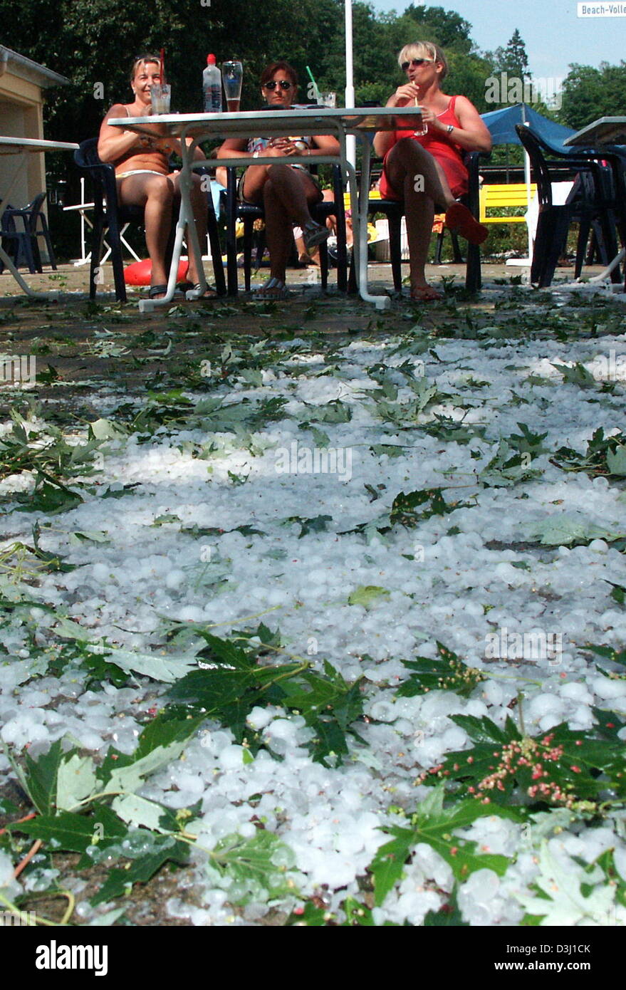 (dpa) - Three people sit at a camping table in a meadow covered with ...