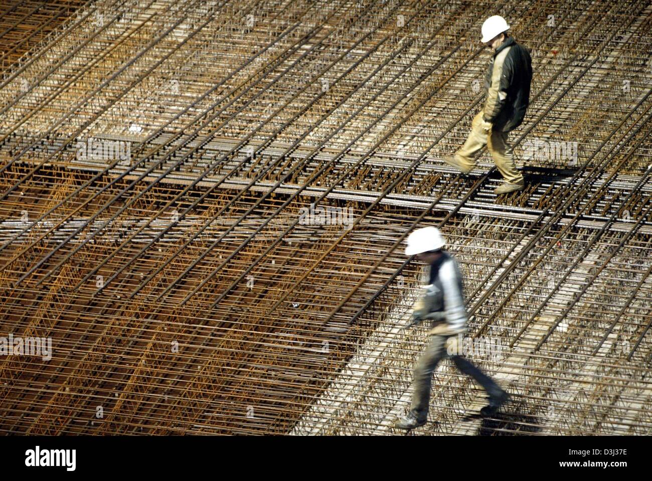 (dpa) - Construction workers walk over a steel grid for a ceiling on a ...