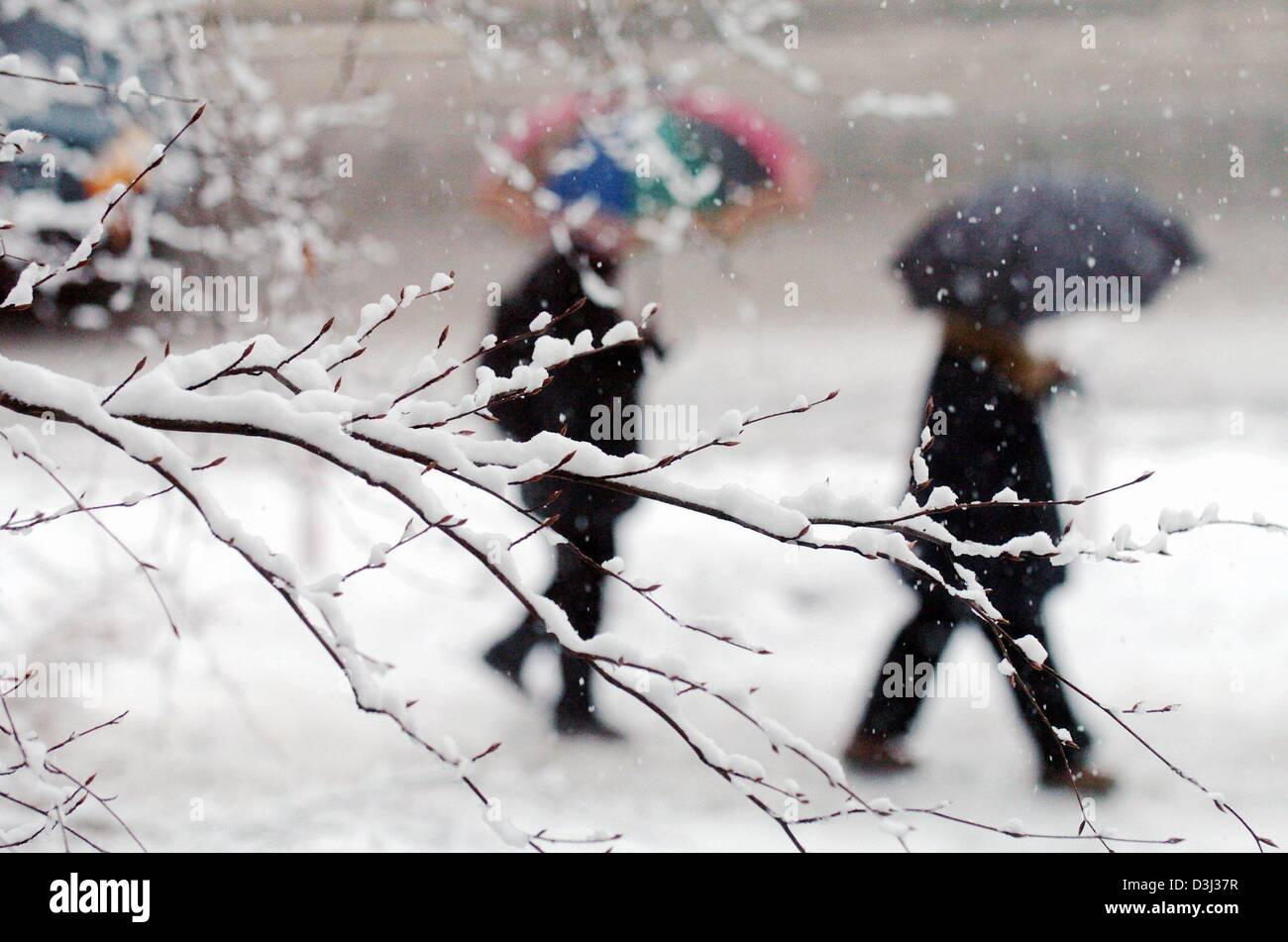 (dpa) - Pedestrians with umbrellas trudge through the snow in Hamburg ...