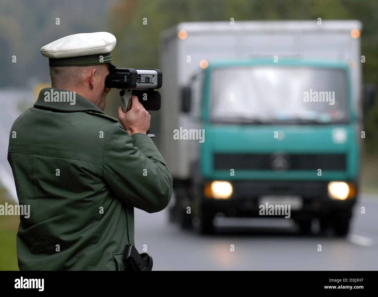 (dpa) - A police officer measures the speed of a lorry with a laser ...