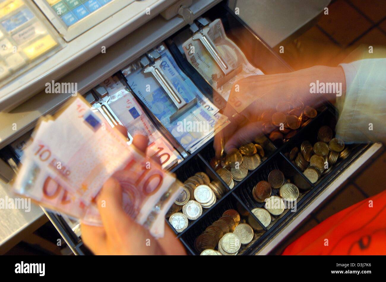 (dpa) - Hands take out Euro notes and change from a cash register in a ...