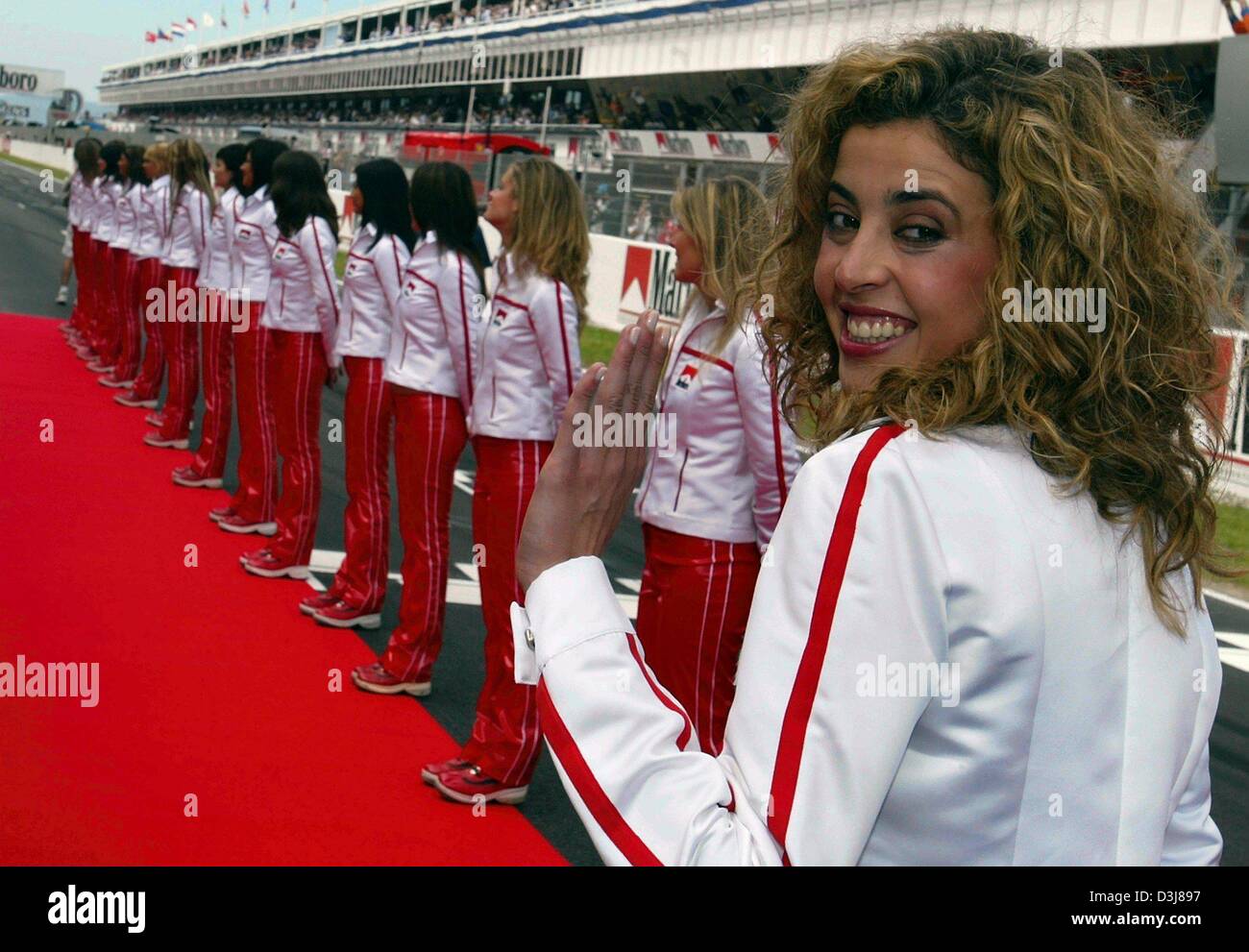 (dpa) - A row of grid girls line up alongside a red carpet while ...