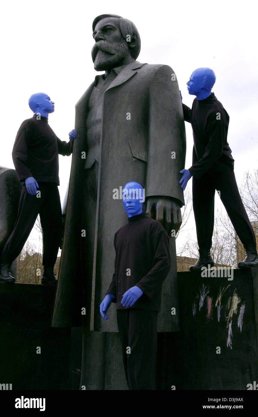 Three members of the Blue Man Group stand next to the statue of ...