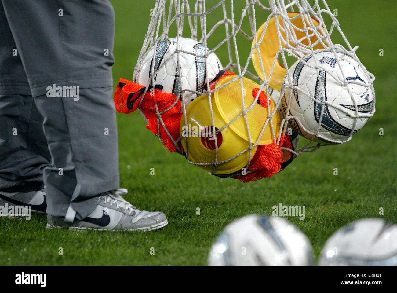 (dpa) - An assistamt collects soccer balls in a net on the pitch of the ...