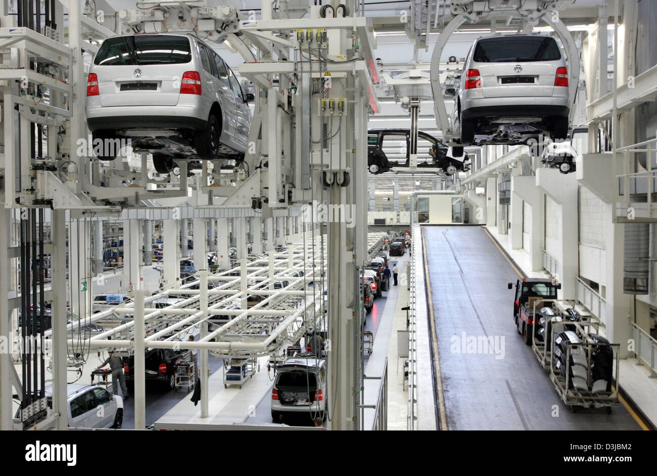 (dpa) - VW Touran cars move along the ceiling above the assembly belts ...