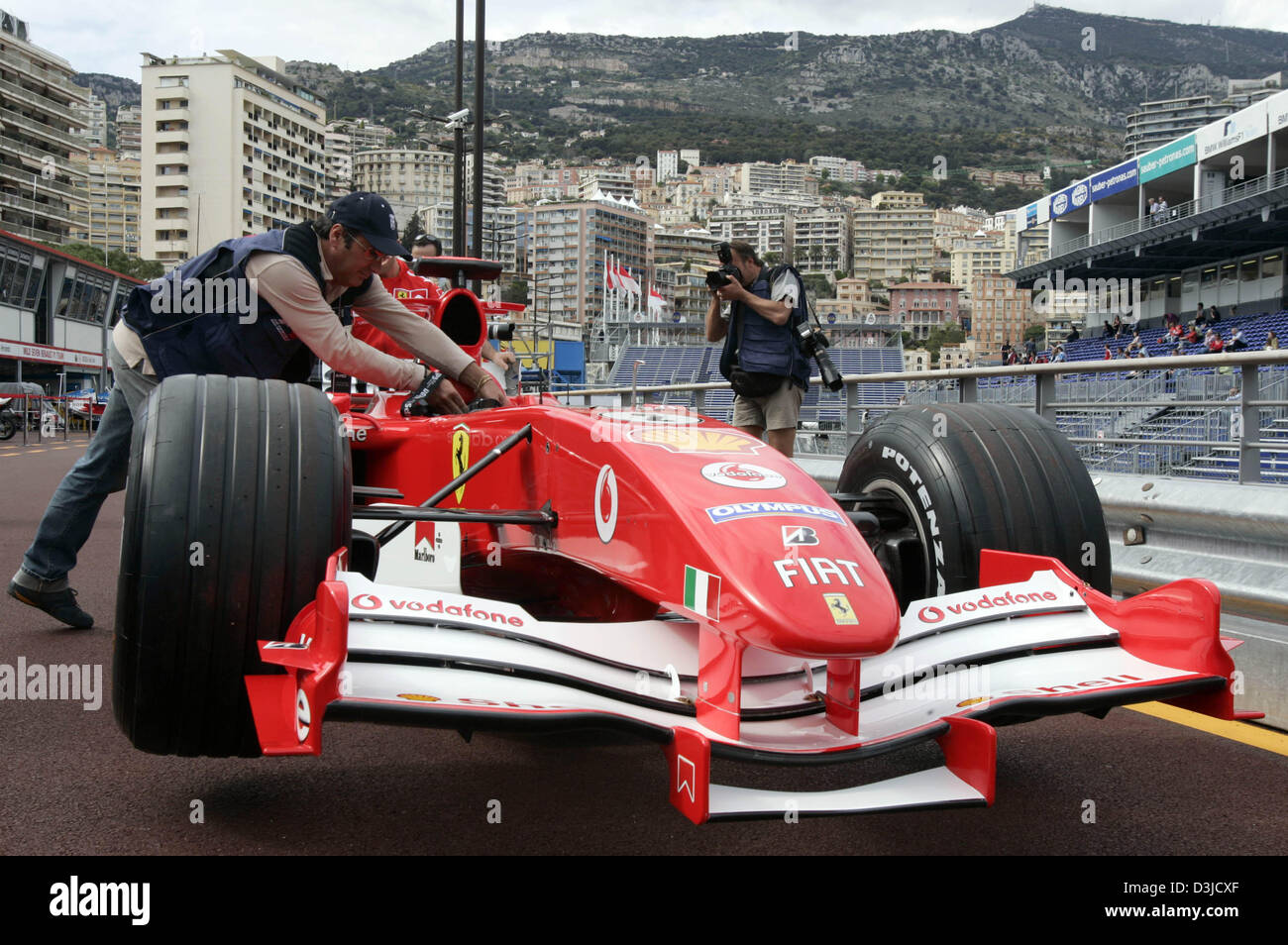(dpa) - Mechanics of the Ferrari team push a racing car through the ...