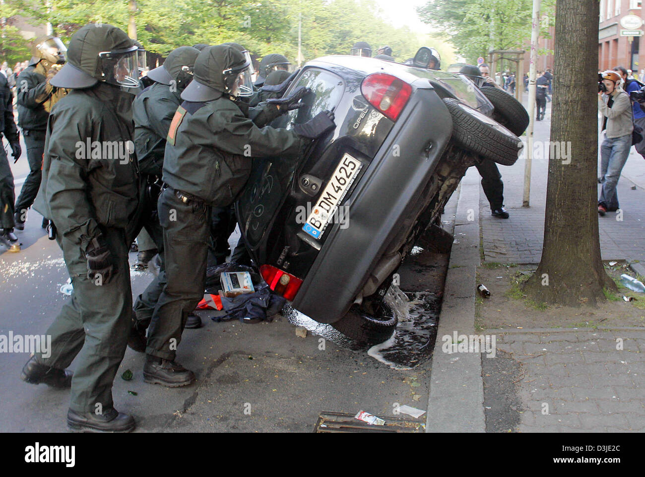 (dpa) - Police put away a turned over car in the streets of Berlin ...