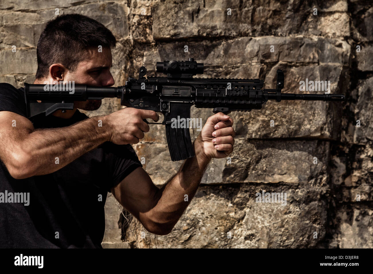 View of a menacing man pointing a machine gun in a black shirt and dark ...