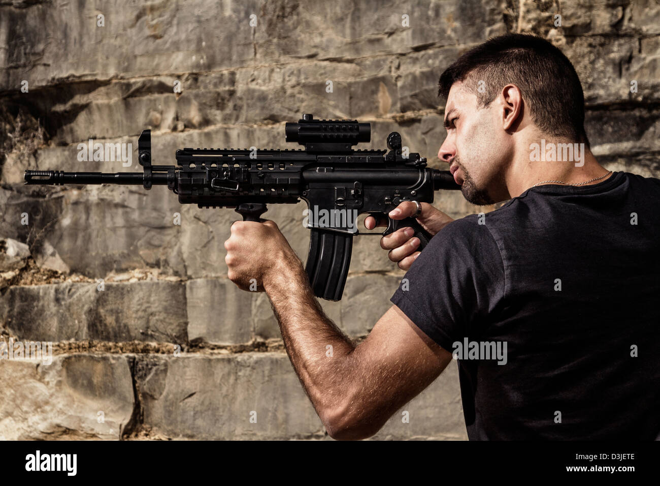 View of a menacing man pointing a machine gun in a black shirt and dark ...