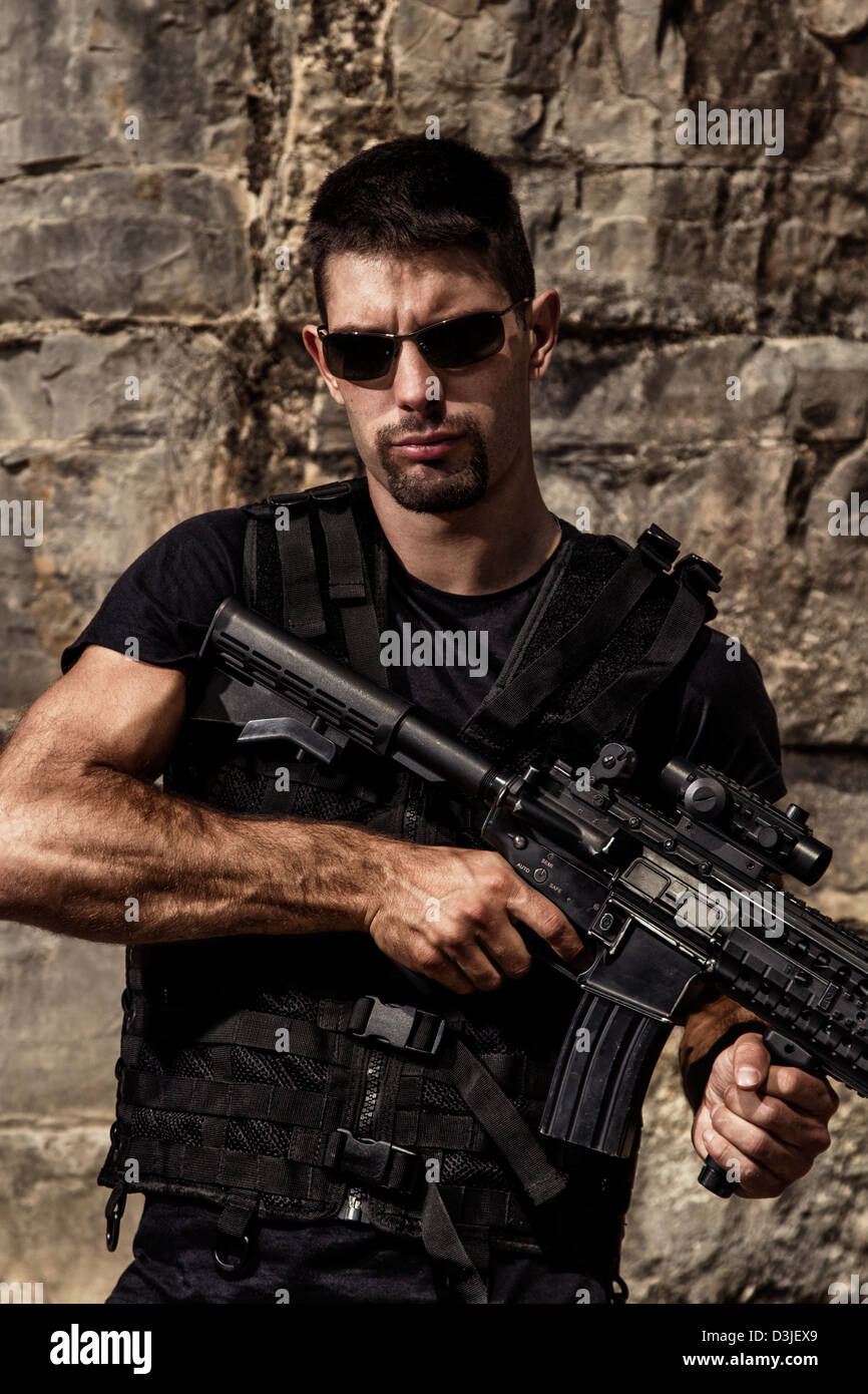 View of a menacing man with a machine gun in a black shirt and dark ...