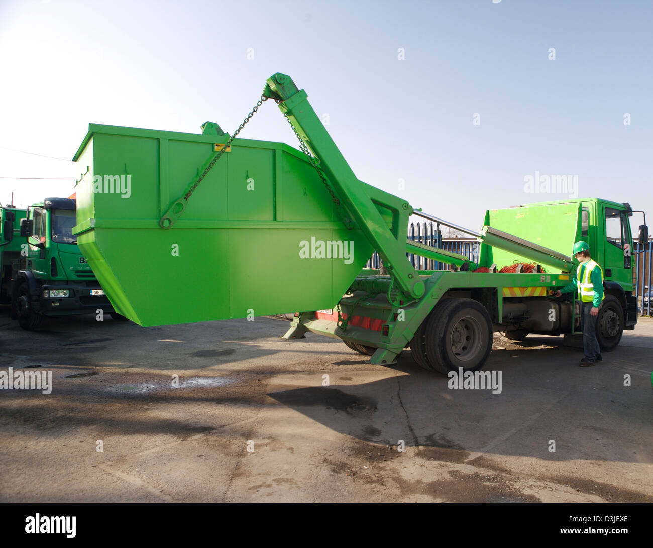 Green skip being hoisted onto a disposal truck Stock Photo - Alamy