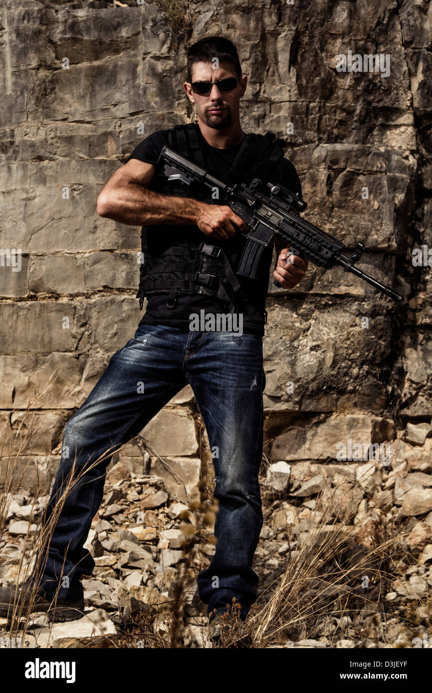 View of a menacing man with a machine gun in a black shirt and dark ...