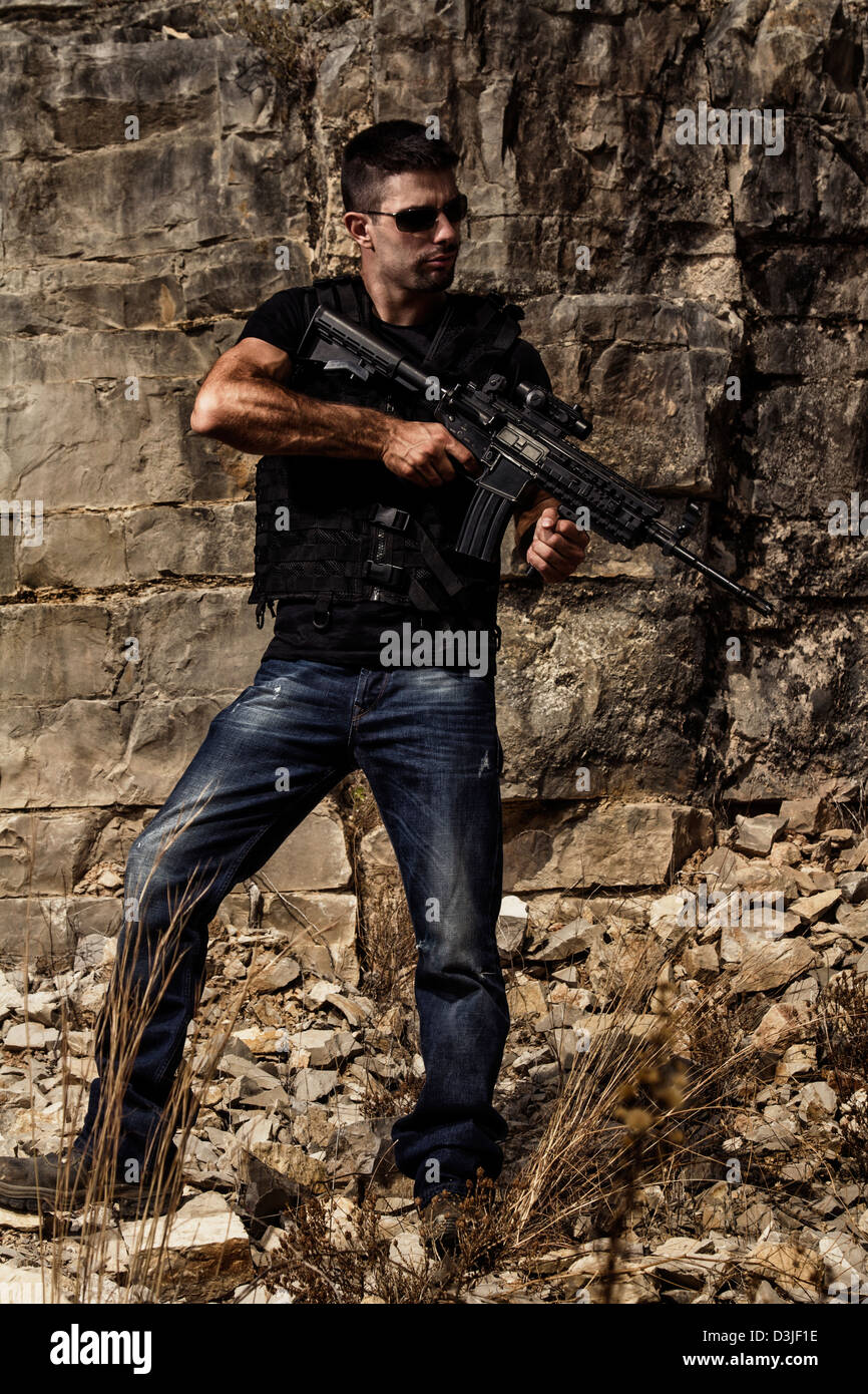 View of a menacing man with a machine gun in a black shirt and dark ...