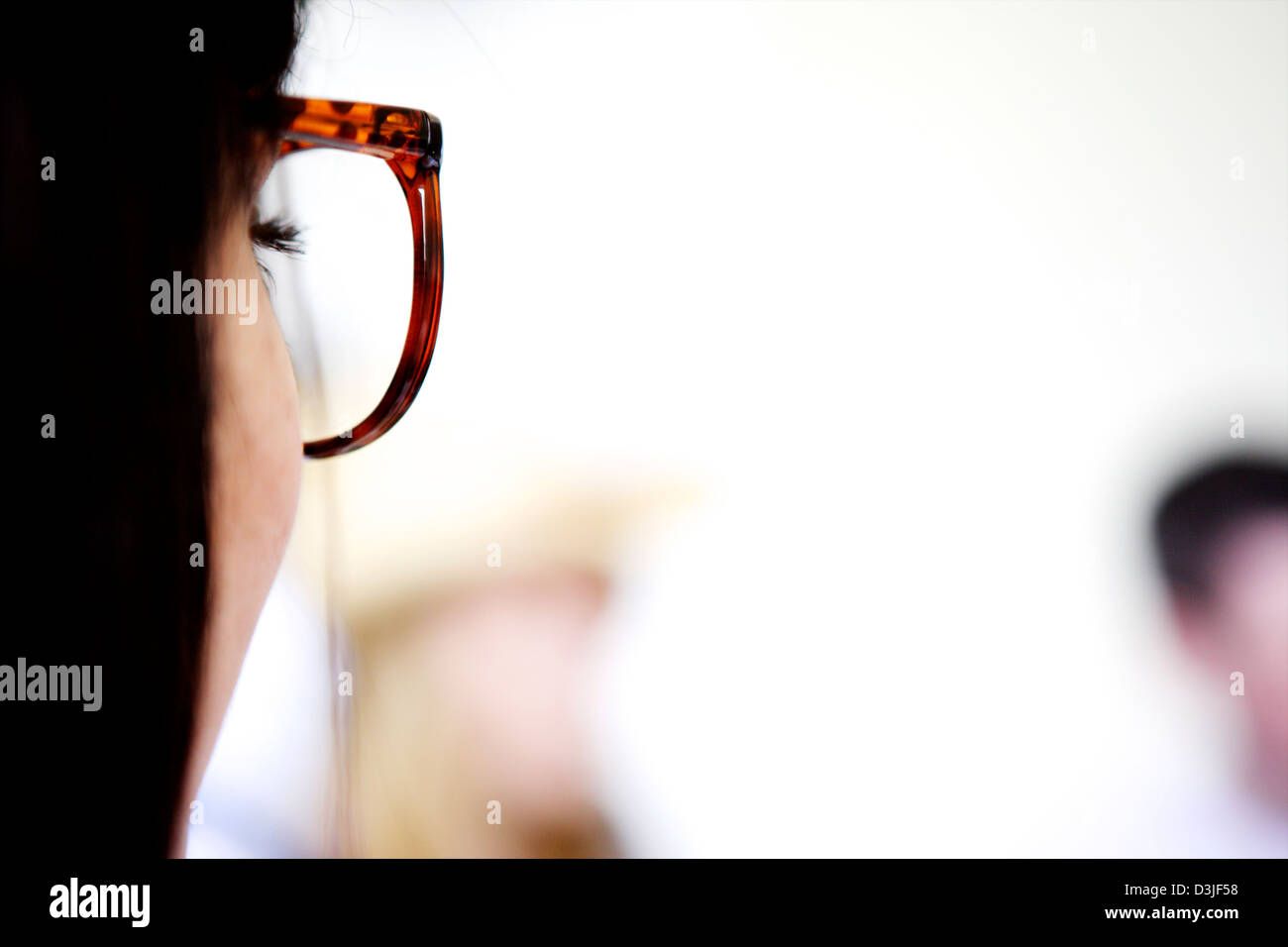 A dark haired wearing glasses (side view of the frame) looks at two ...