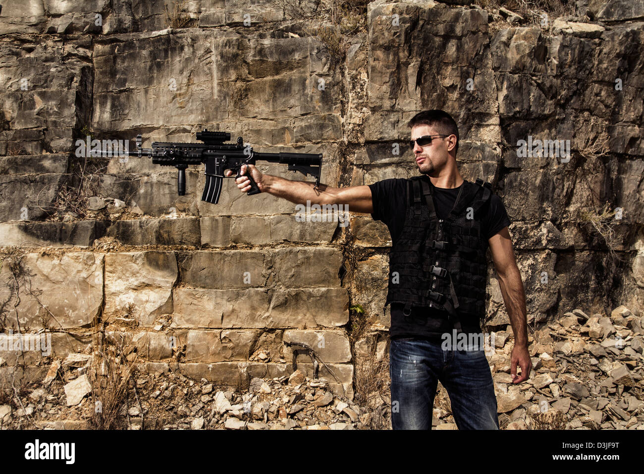 View of a menacing man pointing a machine gun in a black shirt and dark ...