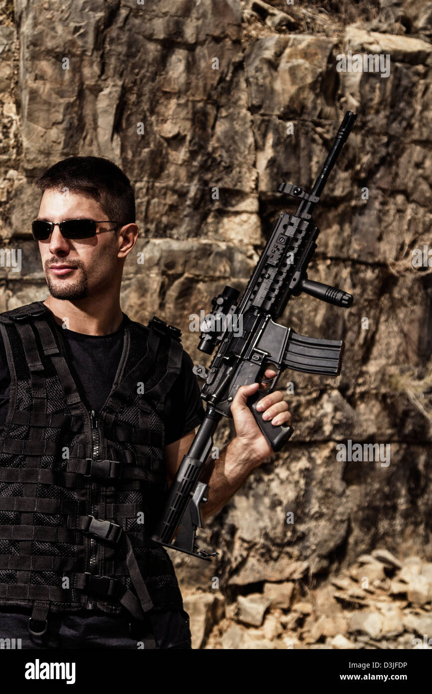 View of a menacing man with a machine gun in a black shirt and dark ...