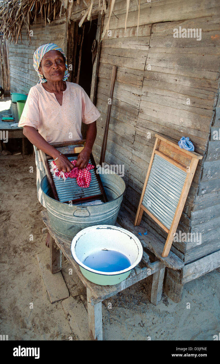 Woman of the Garifuna people washing clothes outside her thatched ...