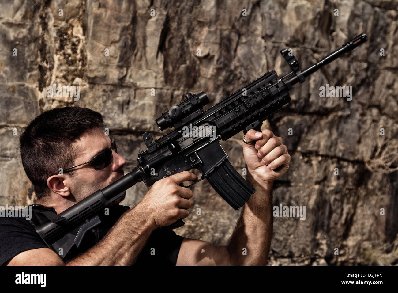 View of a menacing man pointing a machine gun in a black shirt and dark ...