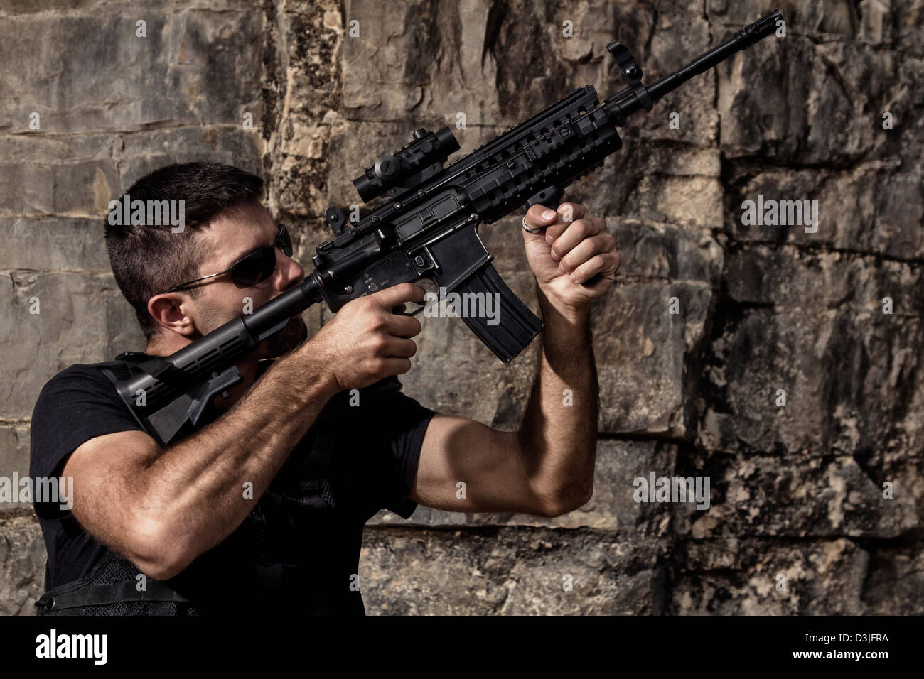 View of a menacing man pointing a machine gun in a black shirt and dark ...