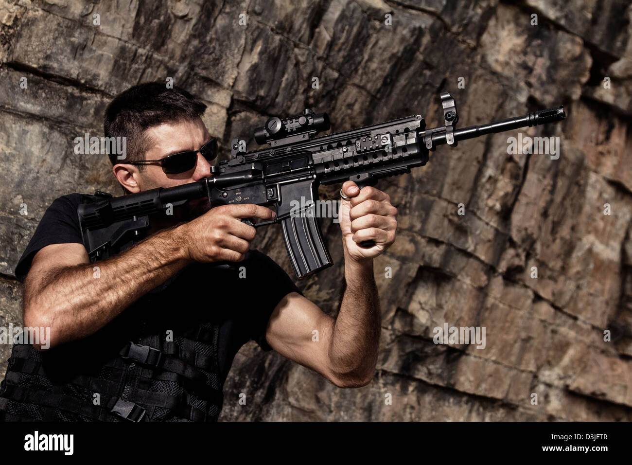 View of a menacing man pointing a machine gun in a black shirt and dark ...