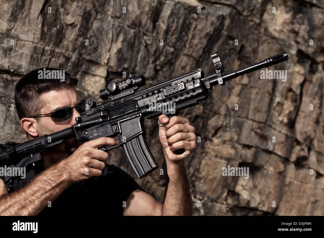 View of a menacing man pointing a machine gun in a black shirt and dark ...