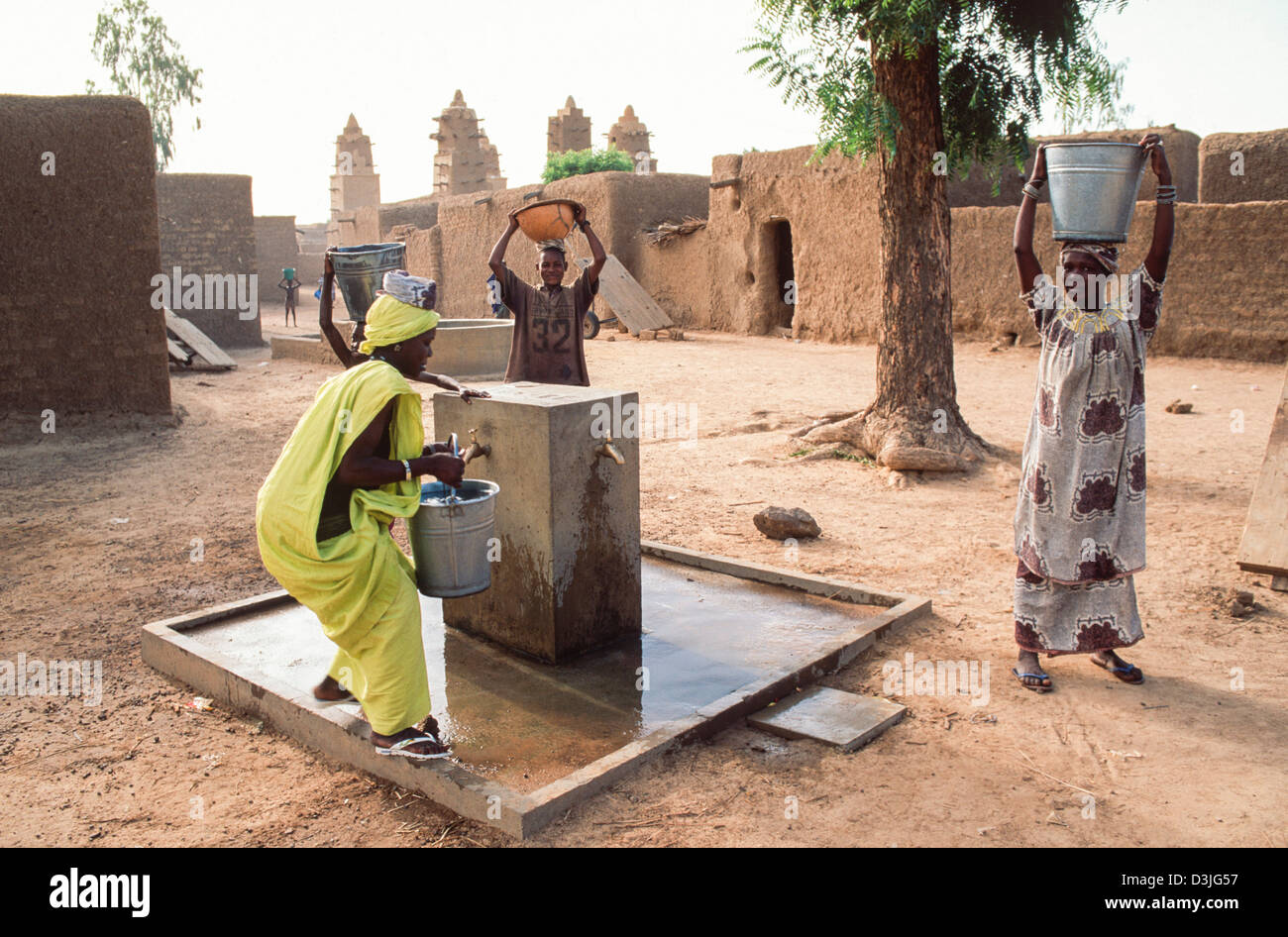 Women collecting water in buckets from the village community water taps ...