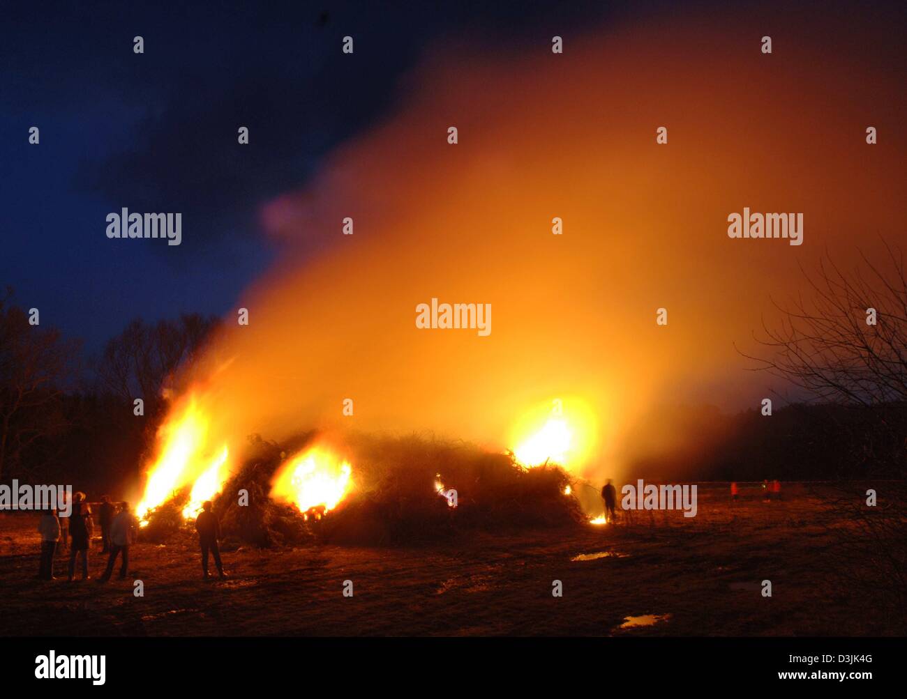 (dpa) - Dozens of spectators stand around a huge bonfire in ...