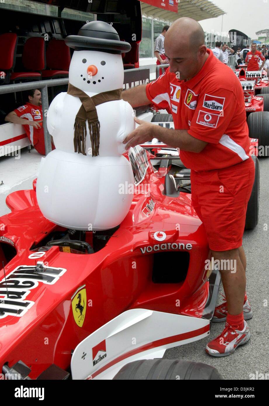 (dpa) - A Ferrari mechanic puts a plastic snowman into the racing car ...