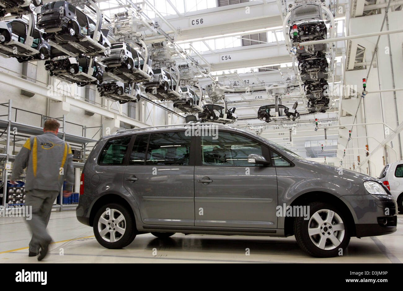 (dpa) - An employee walks around a VW Tourans at the VW assembly plant ...