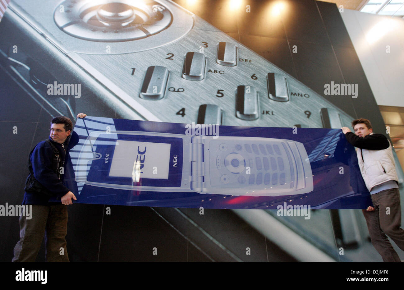 (dpa) - Two men carry a large-sized mobile phone advertisment through ...