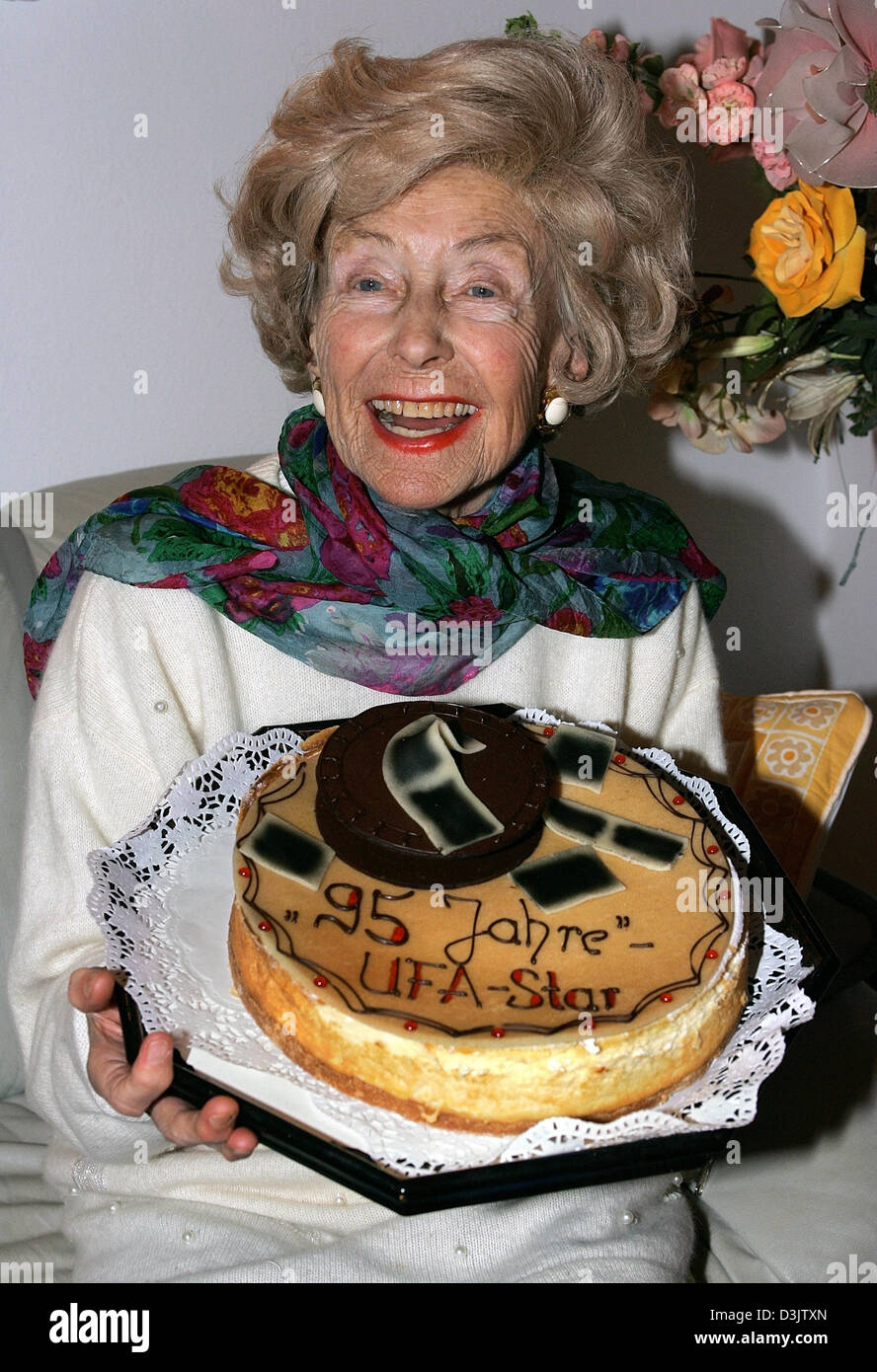 (dpa) - German actress Carola Hoehn smiles and holds up a birthday cake ...