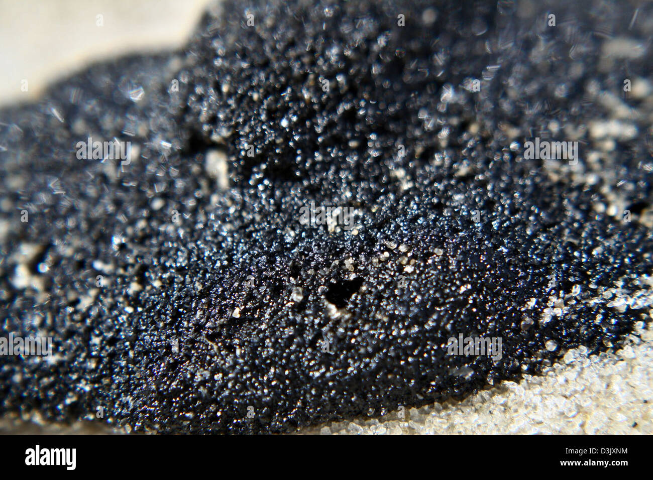 A close-up of a tar ball on a beach, highlighting the environmental ...