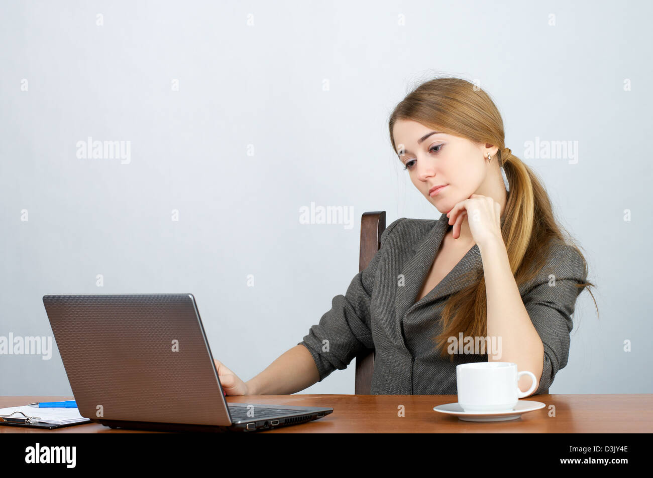 Businesswoman at desk with hand on face, looking into laptop screen ...