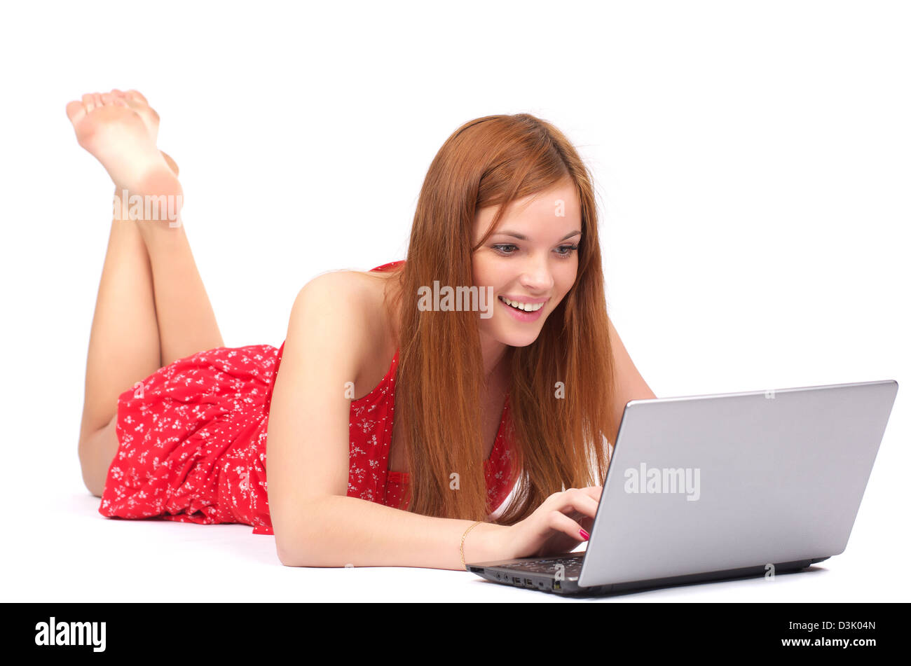 Cheerful young woman working with laptop lying down on white floor ...