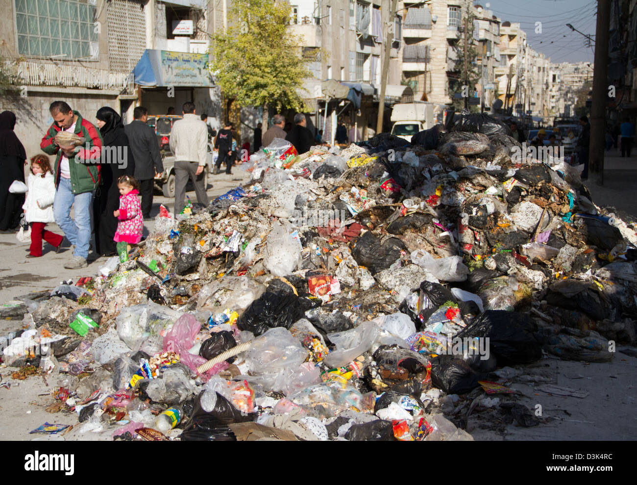 Aleppo, Syria: People walk by trash that is piled up on the streets ...