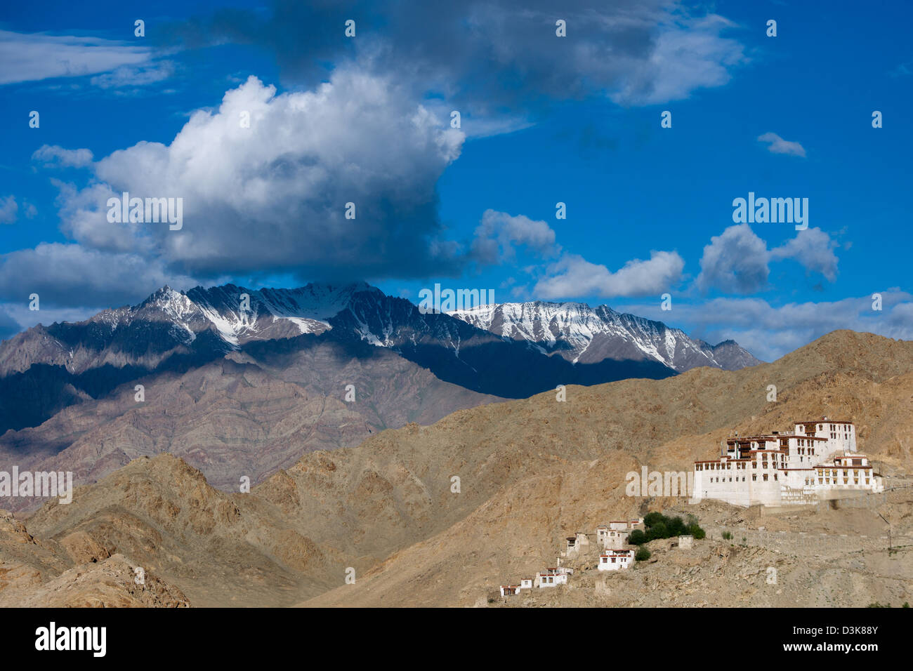 Chemrey Gompa dwarfed by rugged snow-capped mountains and stormy clouds ...