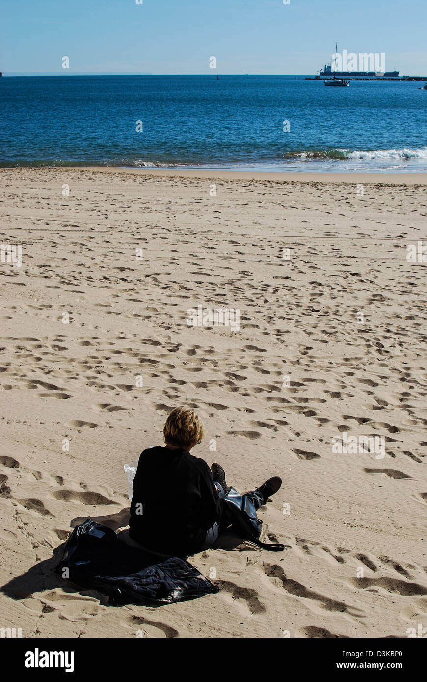 Lady sitting on the beach on her own Stock Photo - Alamy
