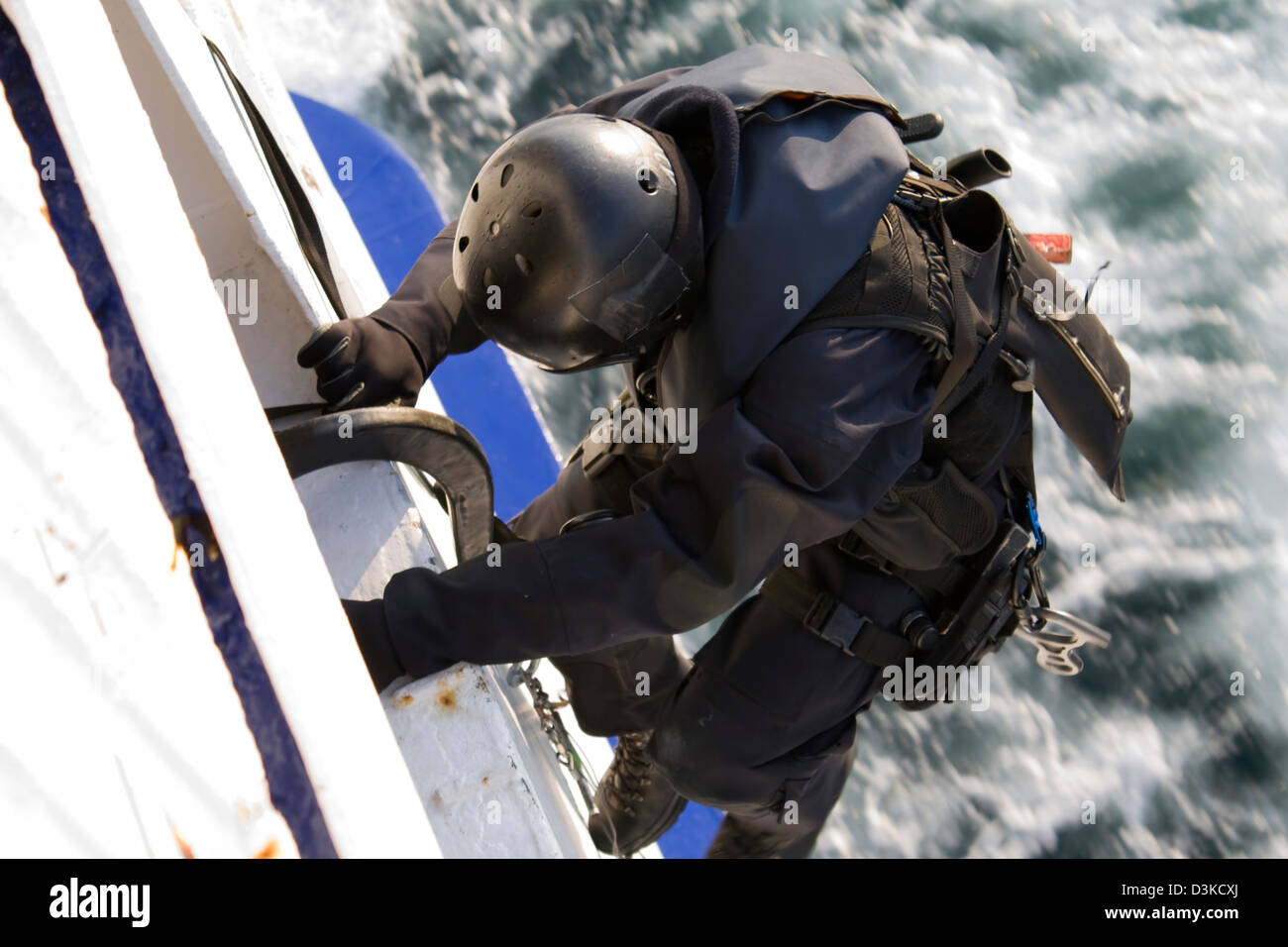 A special forces (SWAT) agent climbs the side of a moving ship using a ...