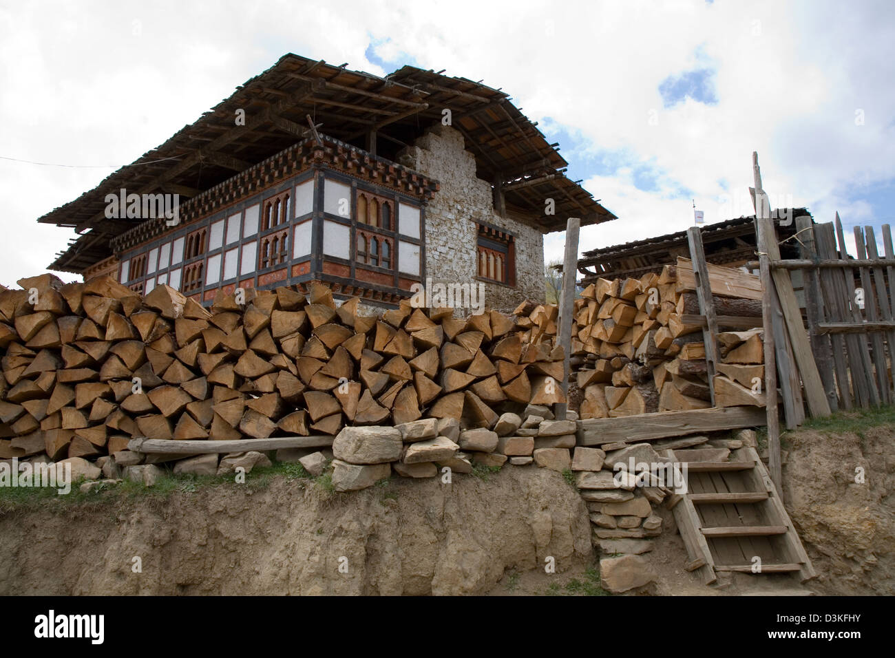Wood pile fronts a house on a hill in the Ura Valley of Bhutan, Asia ...