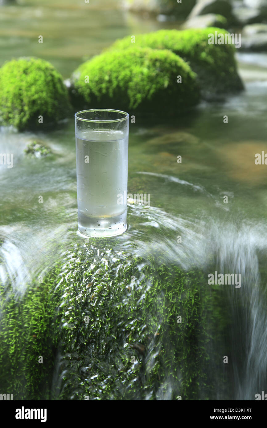 Glass of water near a mountain stream Stock Photo - Alamy