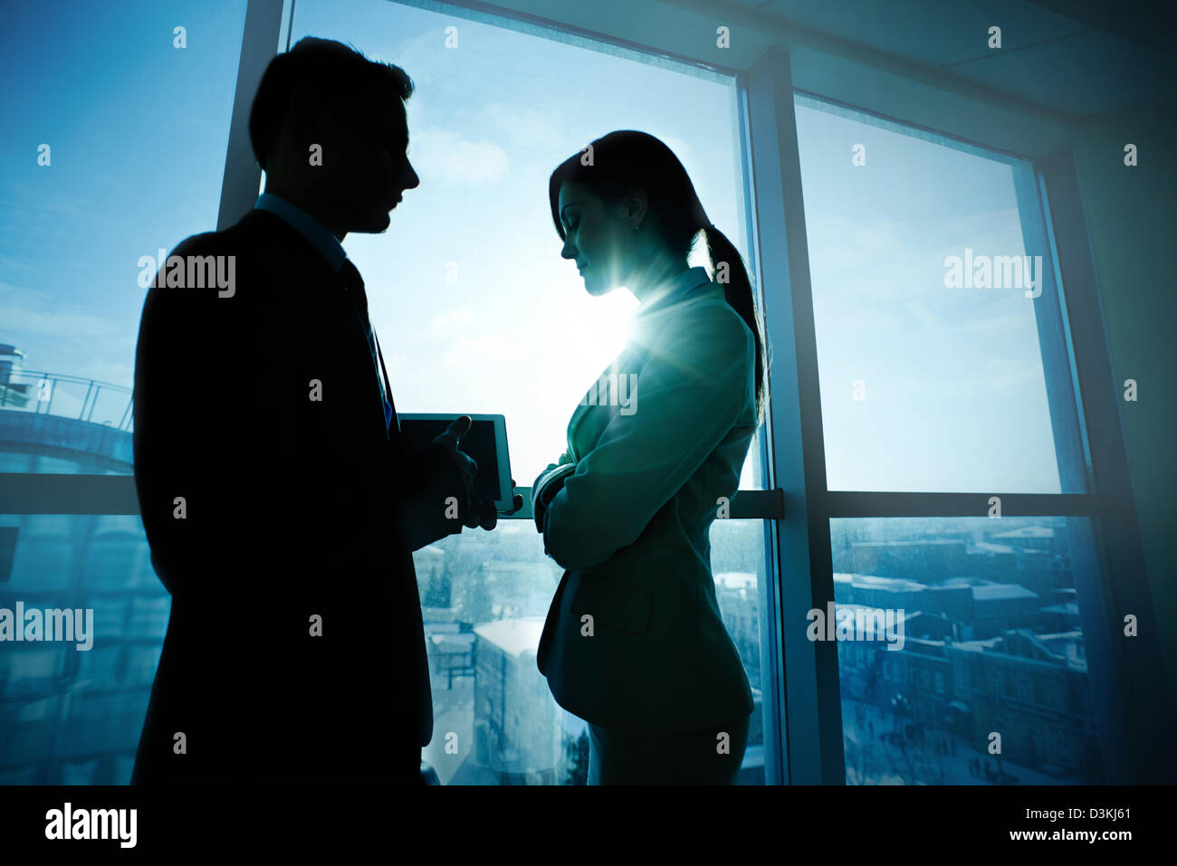 Two business partners standing by the window in office and interacting ...