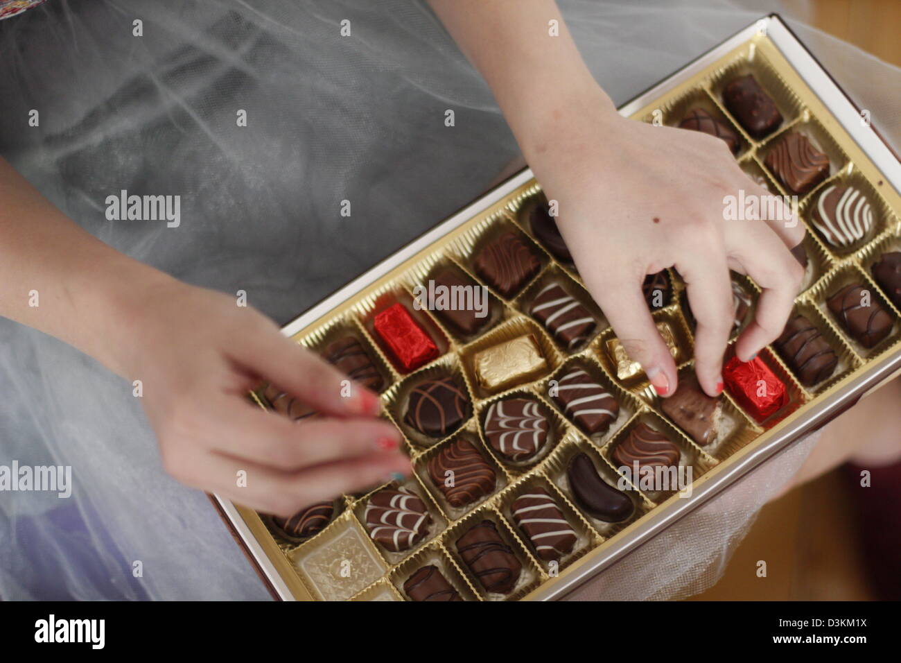 Hands of a young woman picking up chocolates from a box in Bucharest ...
