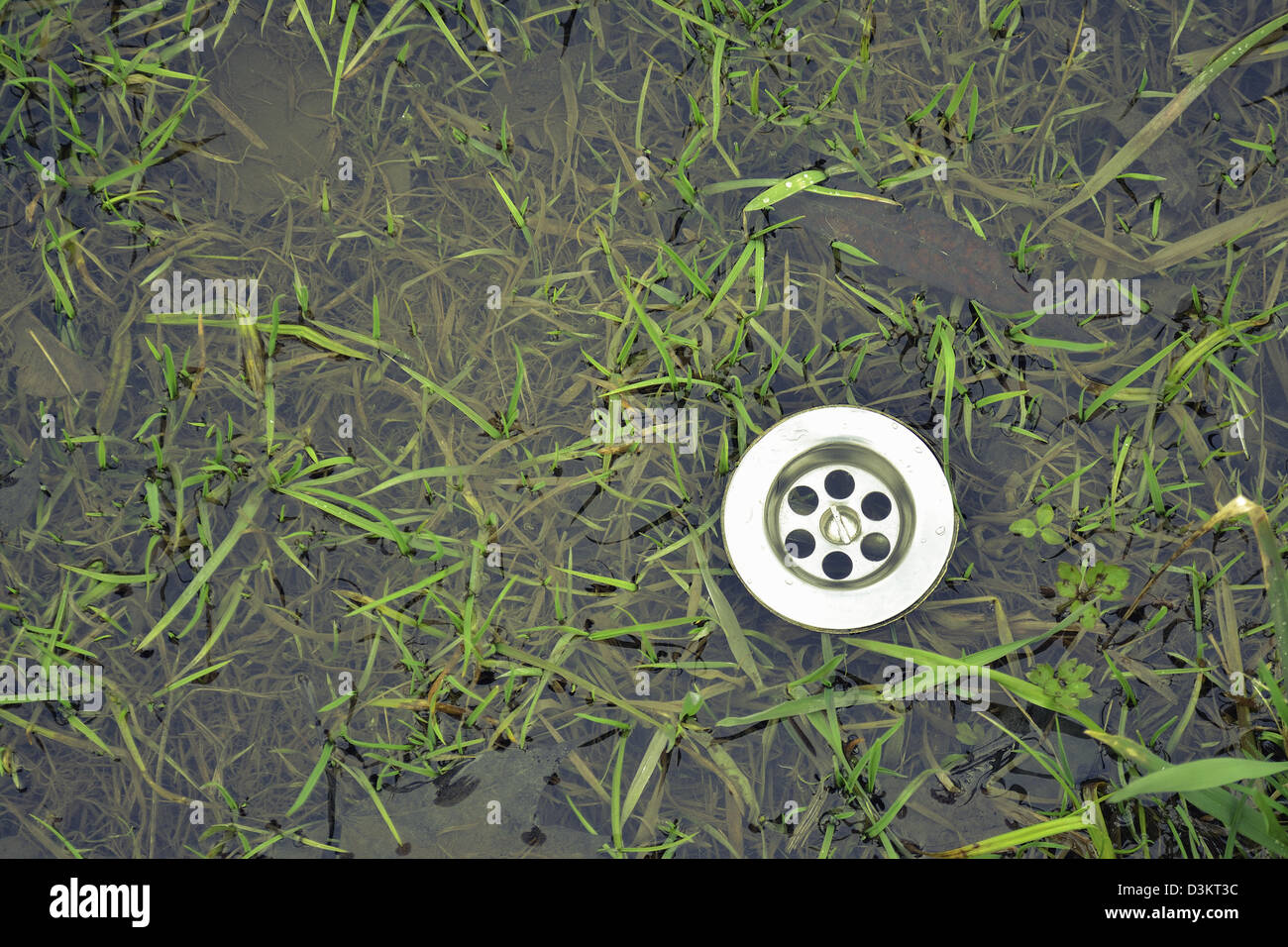 metallic sink hole inside natural puddle background Stock Photo - Alamy