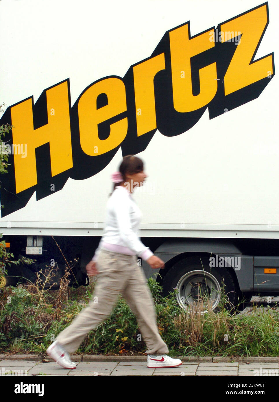 (dpa) - A young woman walks pass the logo of the car rental agency ...