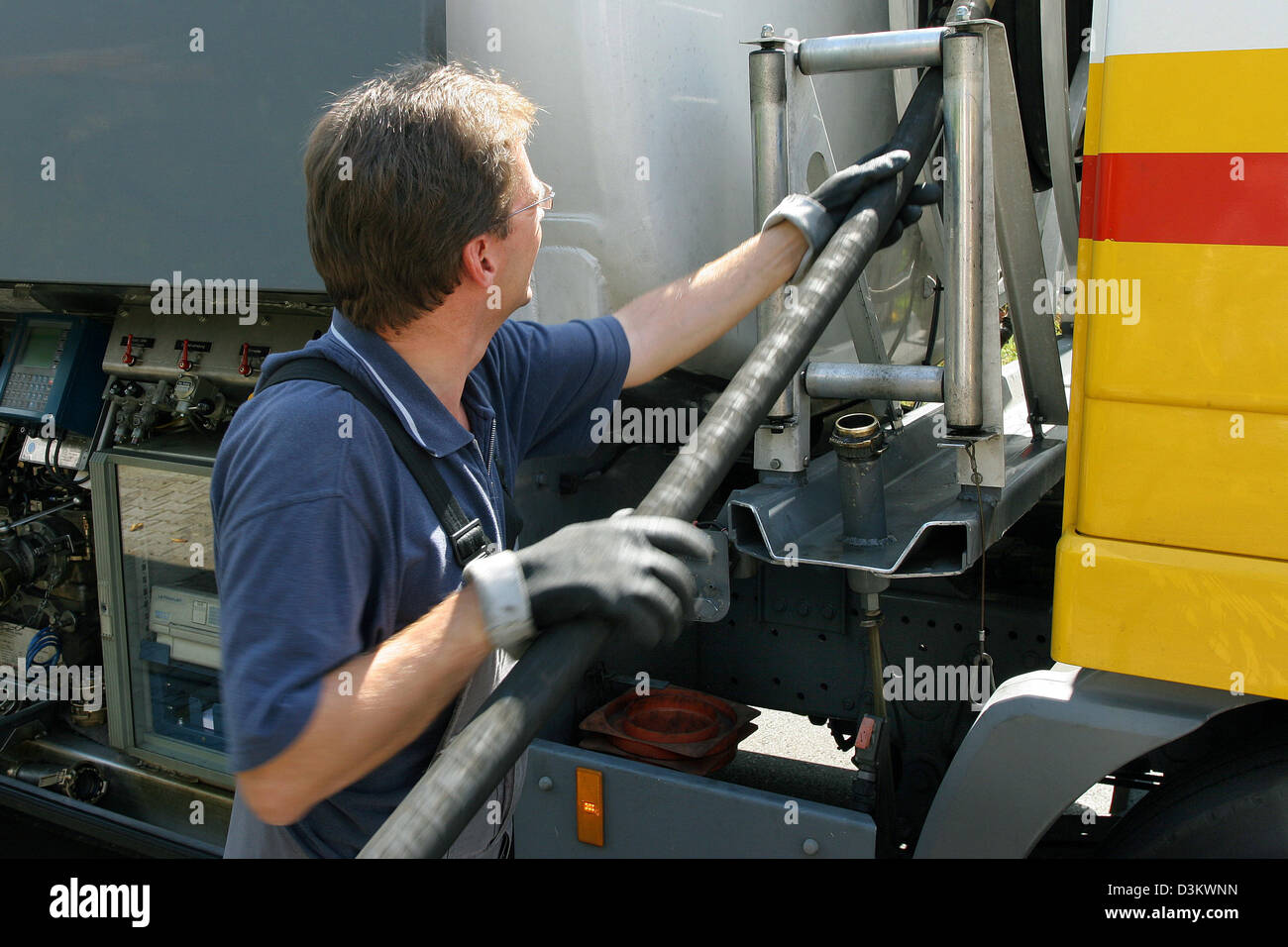 A worker unrolls a tube of a tank lorry loaded with heating oil in ...