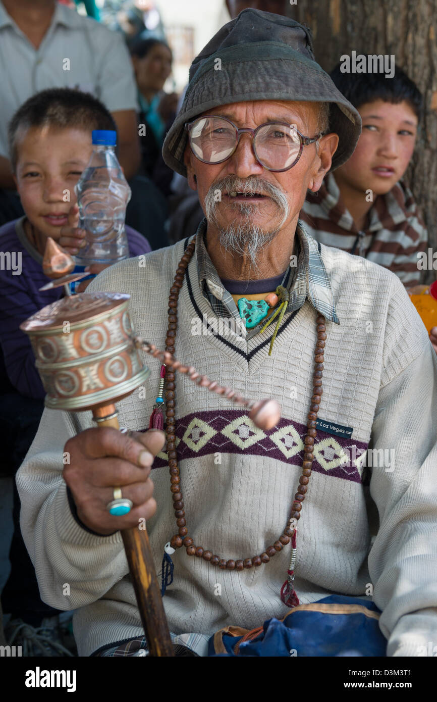 Elderly male pilgrim carrying a prayer wheel, with two young boys ...