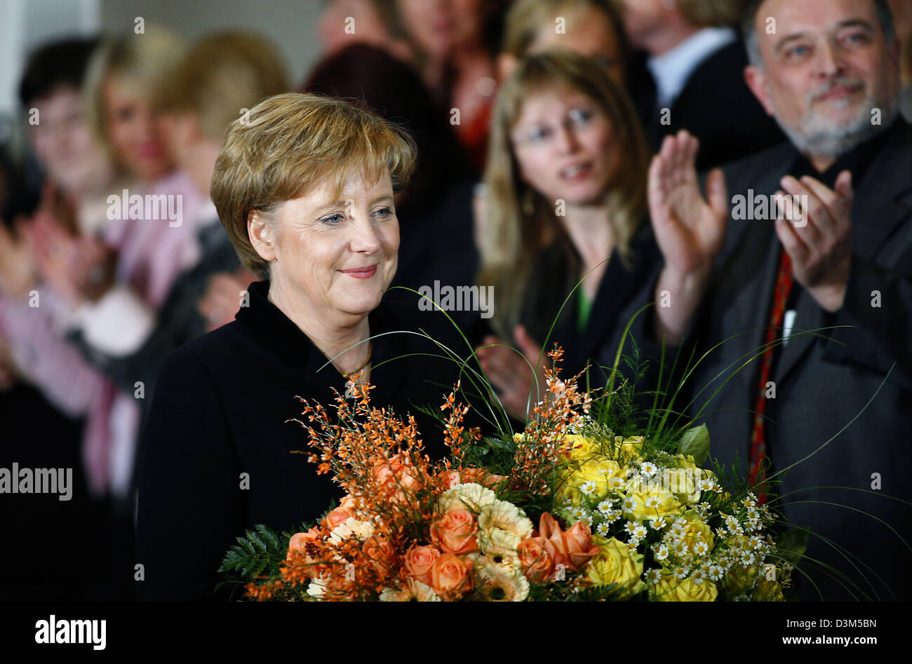 (dpa) - German Chancellor Angela Merkel holds a bunch of flowers in her ...